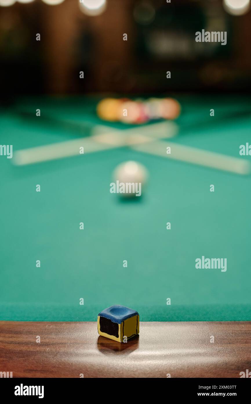 Small snooker chalk for rubbing billiard cue tip lying on wooden ...