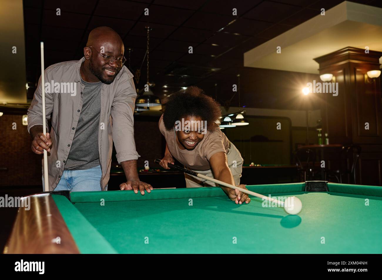 Happy young African American couple playing billiards wile smiling ...