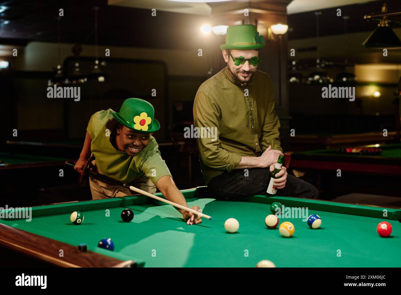 Happy young intercultural couple playing billiards while guy with ...