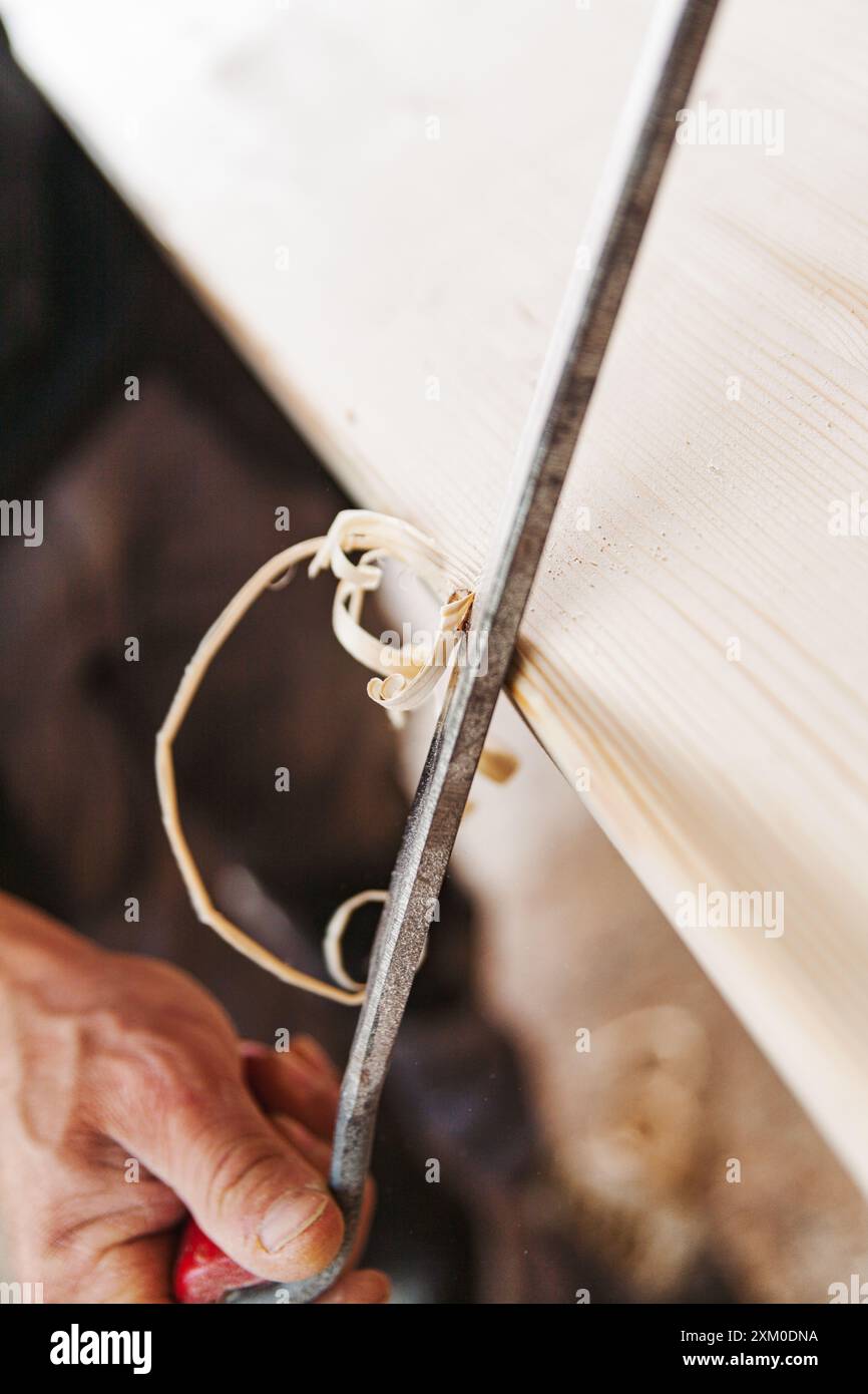 Skilled carpenter shaping wood with hand plane in cozy workshop ...
