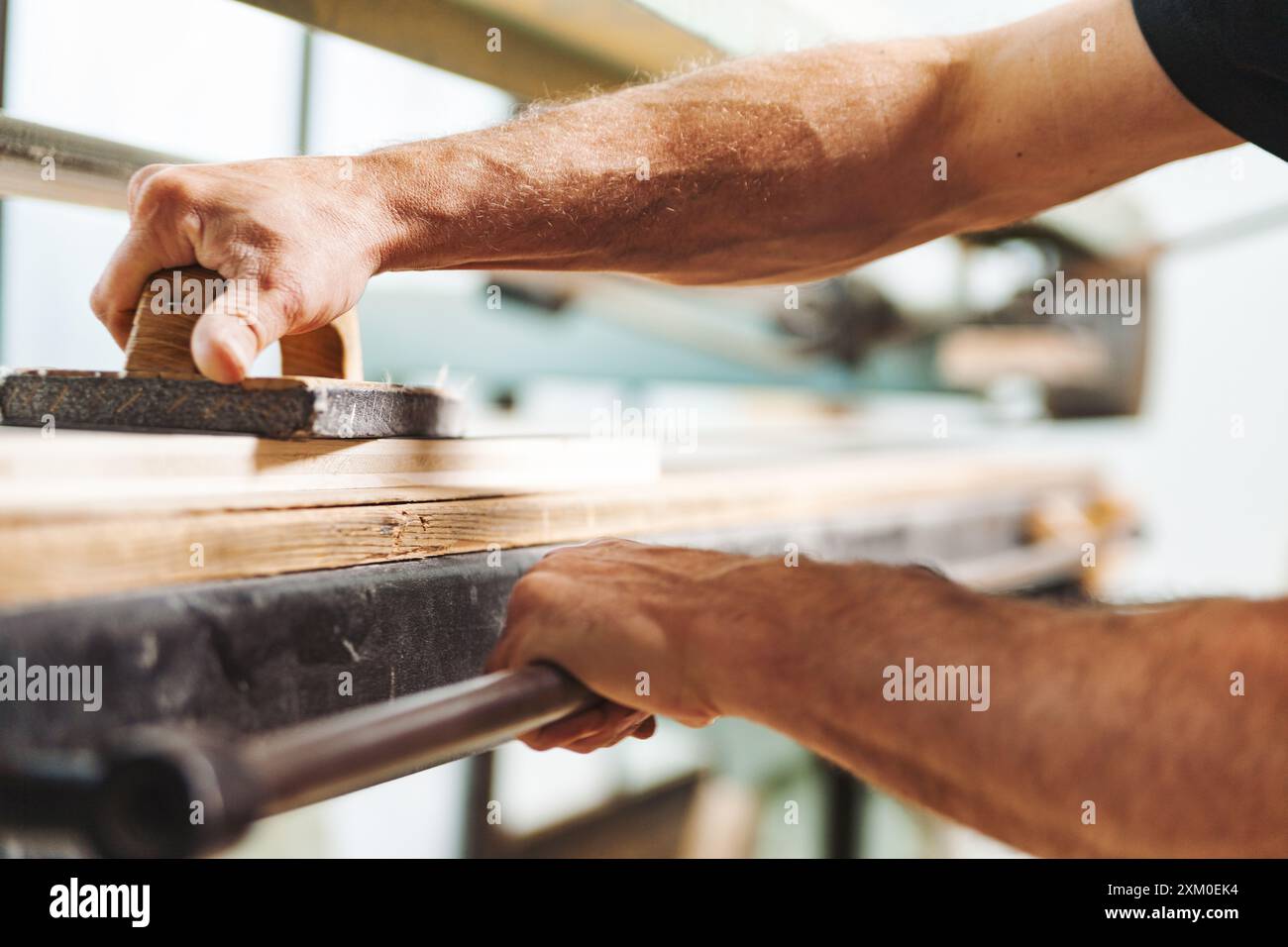 Close up of a carpenter's hands using a hand plane to smooth a wood ...
