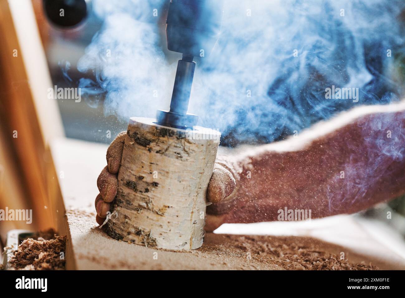 Carpenter is using a drill press to drill a hole in a piece of wood ...
