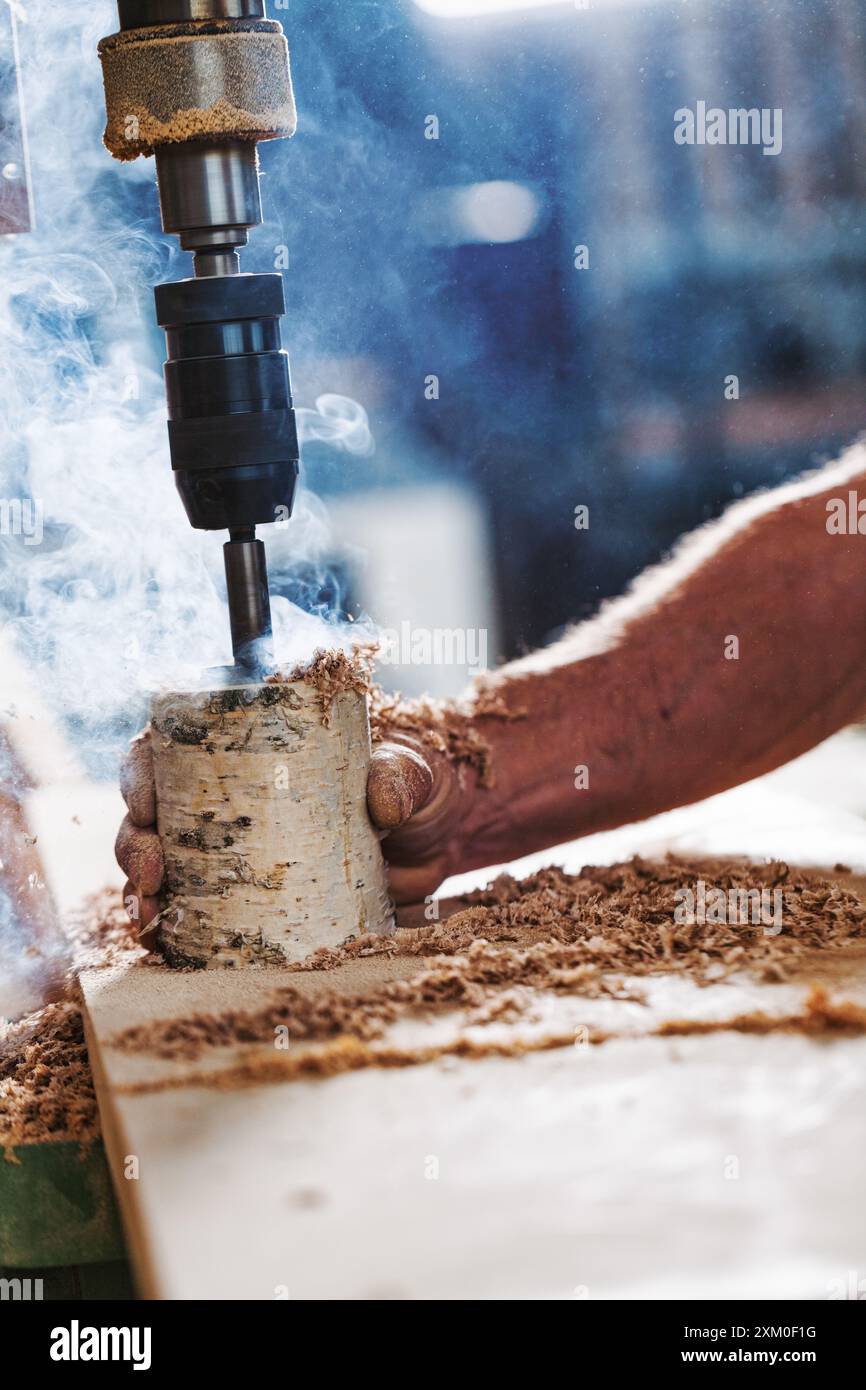 Craftsman drilling wood in workshop, sawdust fills air, showcasing ...