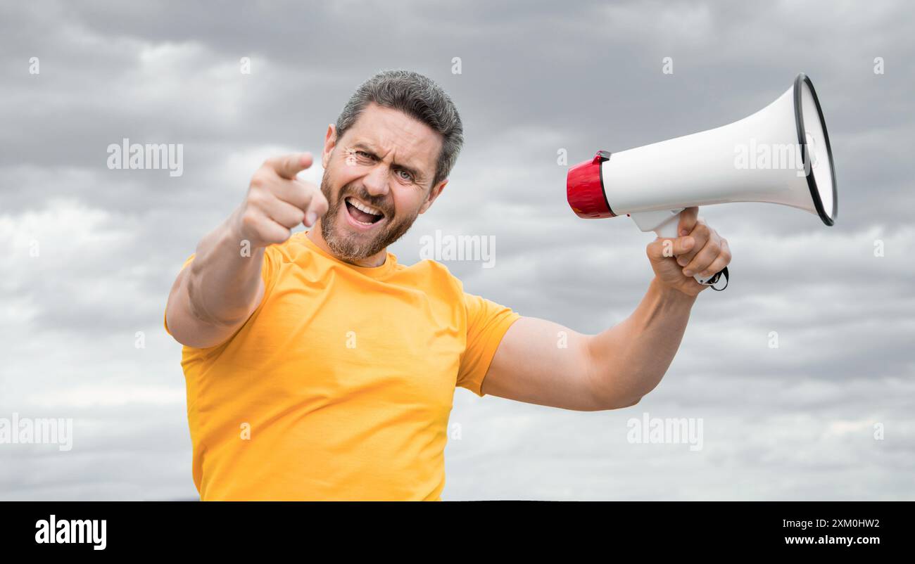 man in yellow shirt with bullhorn on sky background Stock Photo - Alamy