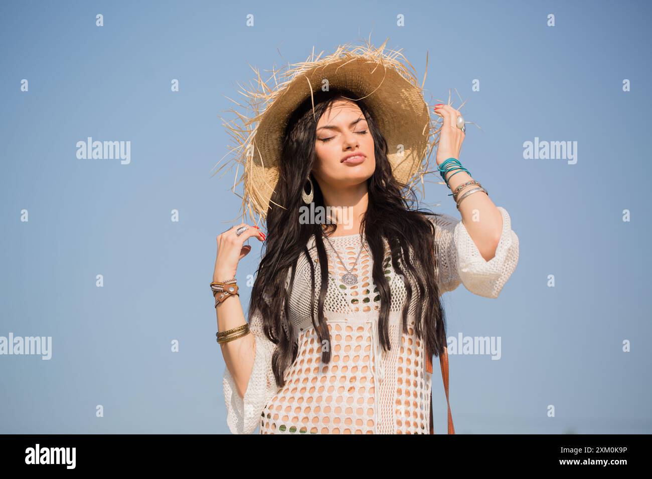 Beautiful woman in a big straw hat, dress and jewelry relaxing on the ...