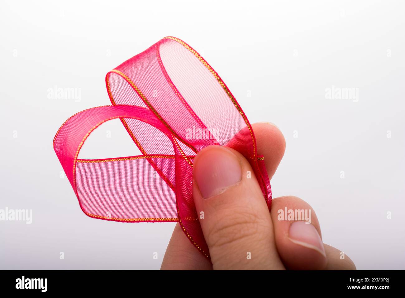 Hand holding a pink color ribbon in hand Stock Photo - Alamy