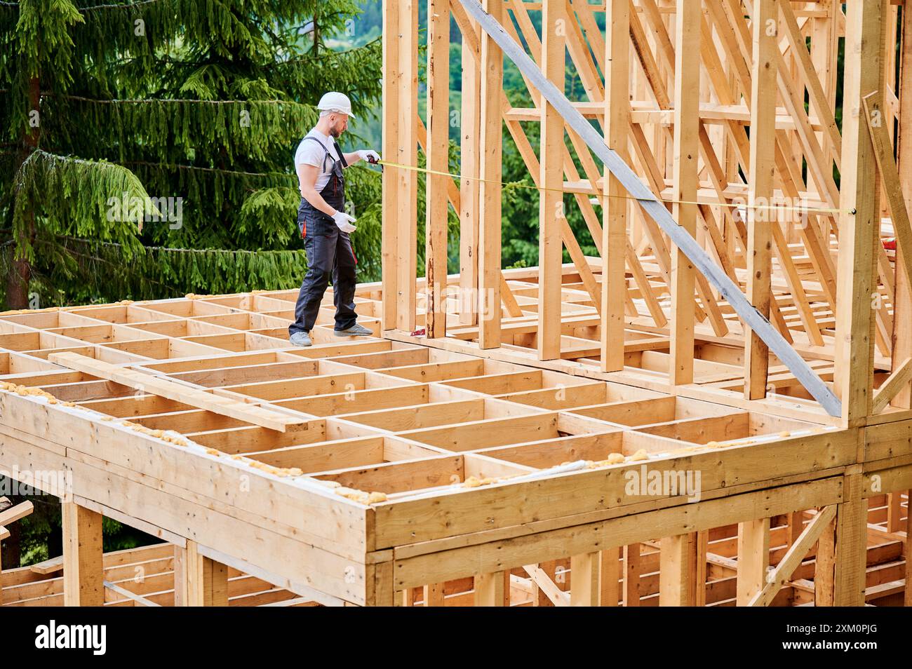 Carpenter constructing house with wooden frame. Man measures distance ...