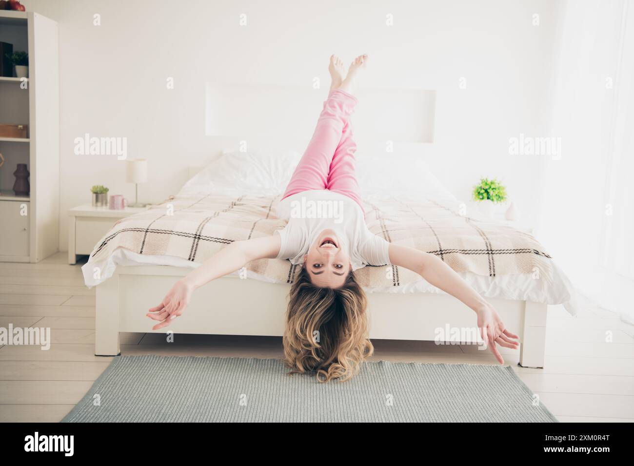 Photo of positive cheerful gitl lying bed upside down in interior room ...