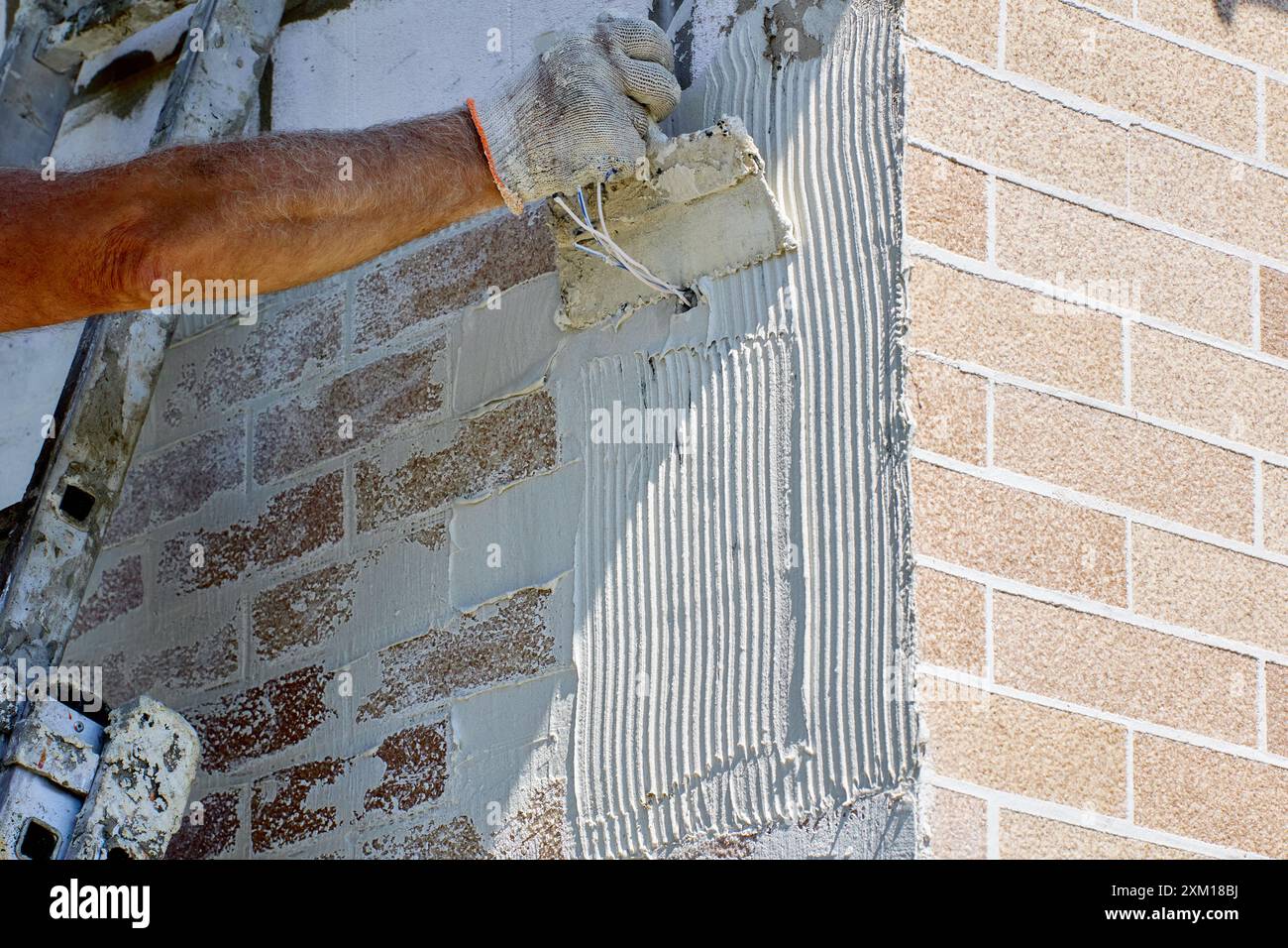Using notched trowel, construction worker applies an even layer of ...