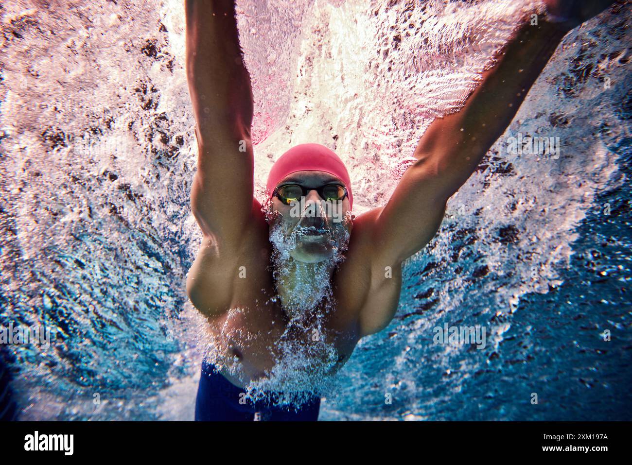 Photo of athletic male swimmer, sportsman wearing pink cap and goggles ...