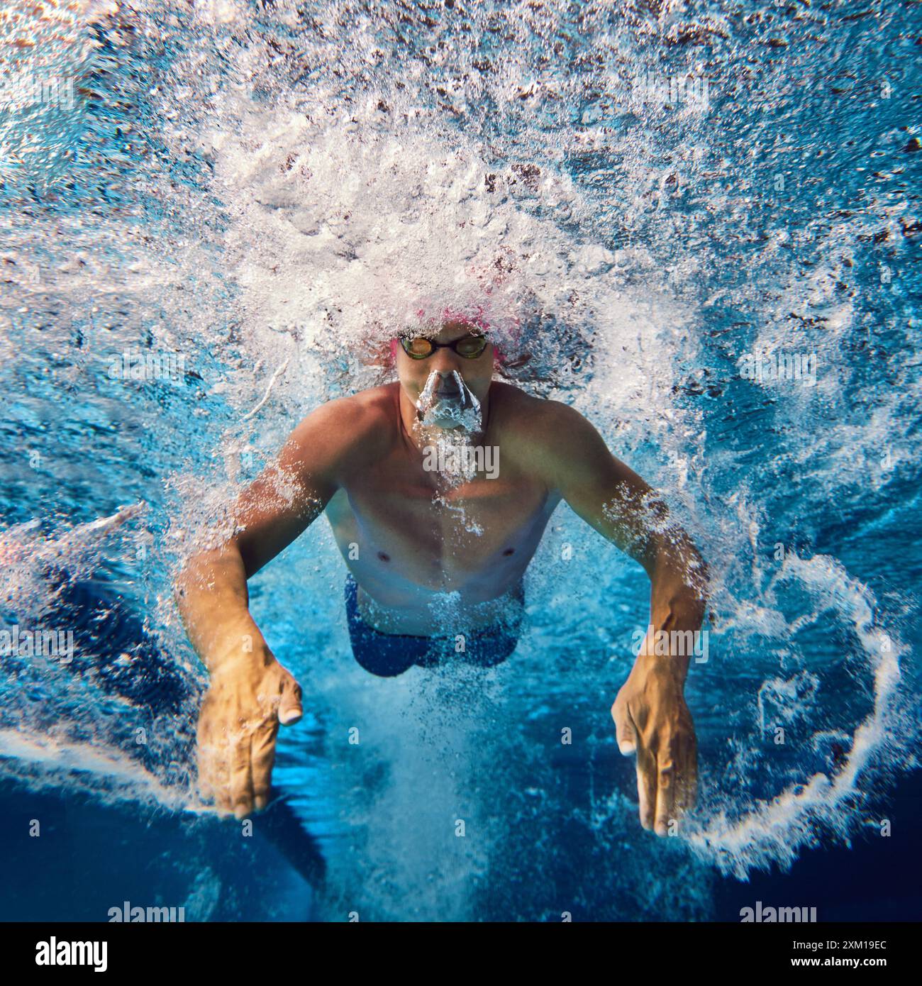 Focused swimmer, seen underwater during training, wears pink cap and ...