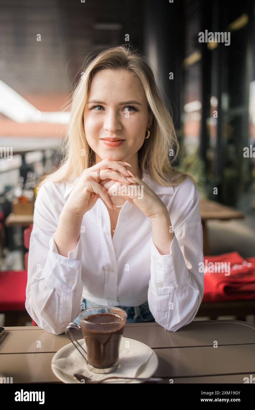 Gen z blonde woman drinks hot chocolate in summer cafe. Tasty beverage ...
