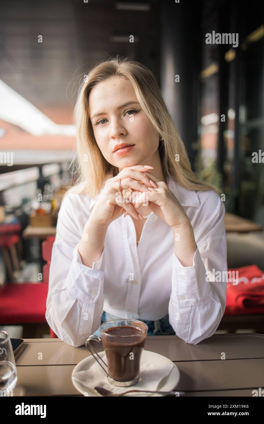 Gen z blonde woman drinks hot chocolate in summer cafe. Tasty beverage ...