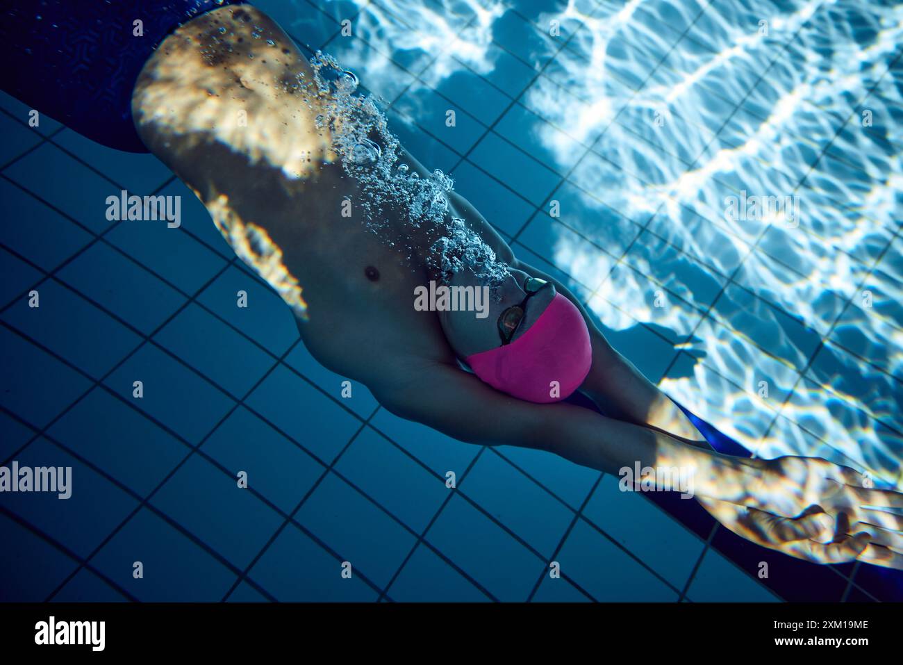 Swimmer, wearing pink cap and blue swim trunks, in training, his ...