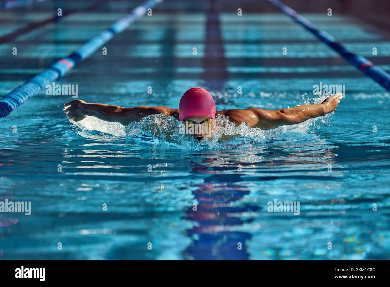 Man, swimmer in pink cap and goggles powers through water with ...