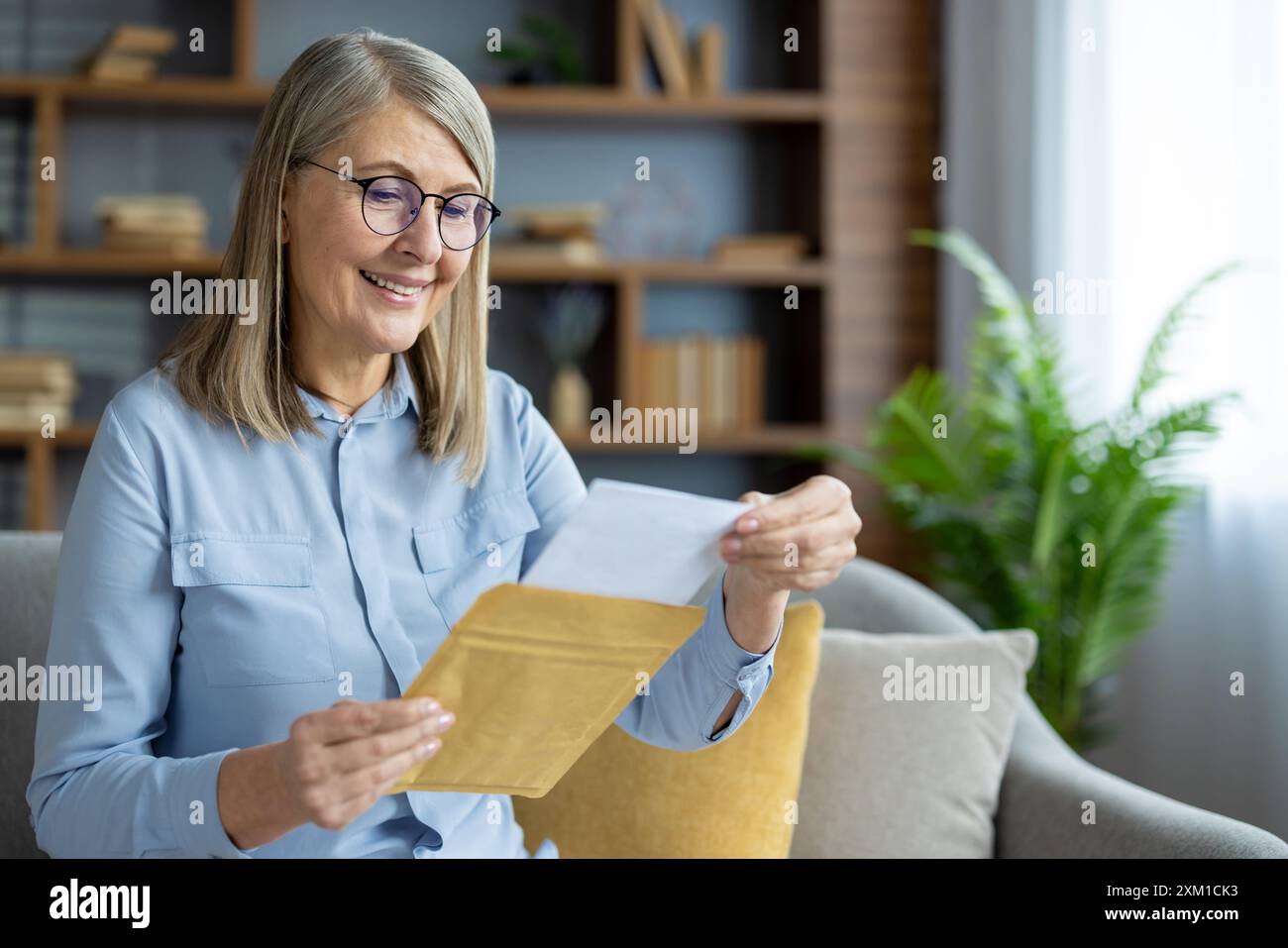 Senior woman reading heartfelt letter at home, experiencing joy and gratitude. Happy moment ...