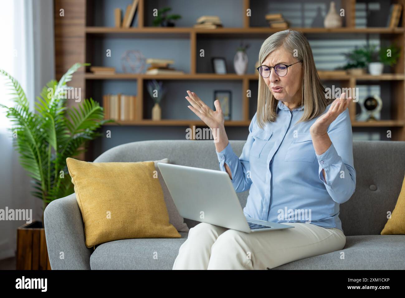 Senior woman displaying frustration during video call on laptop while ...