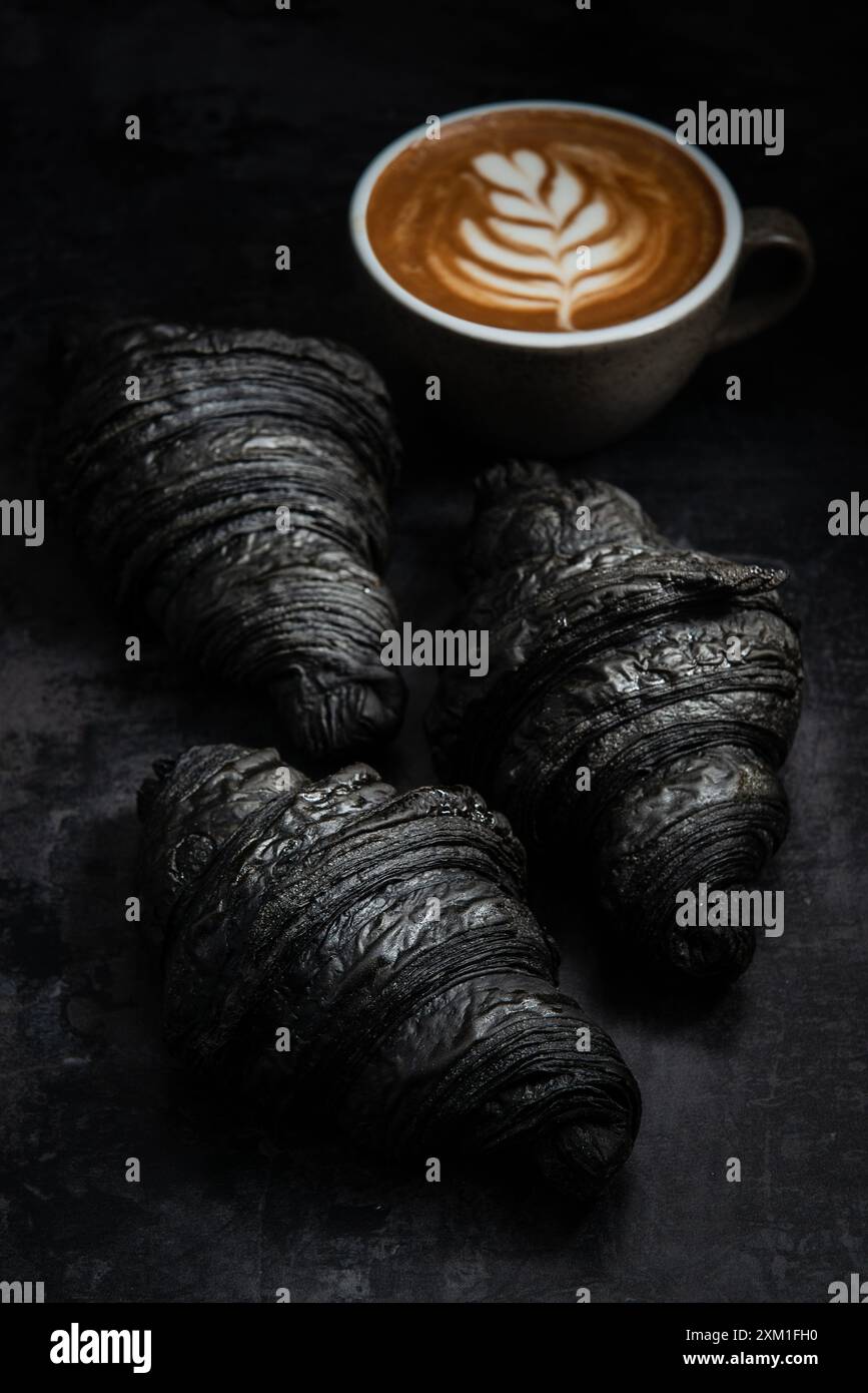 Black gourmet croissants with a cup of cappuccino on a black background ...