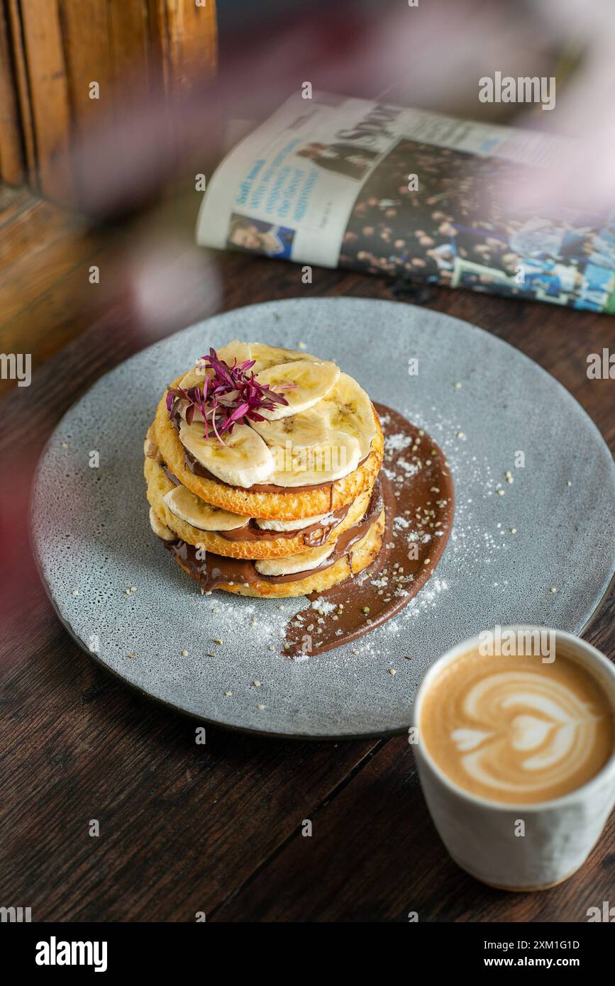 Homemade fluffy banana pancake with chocolate on a coffee shop table ...