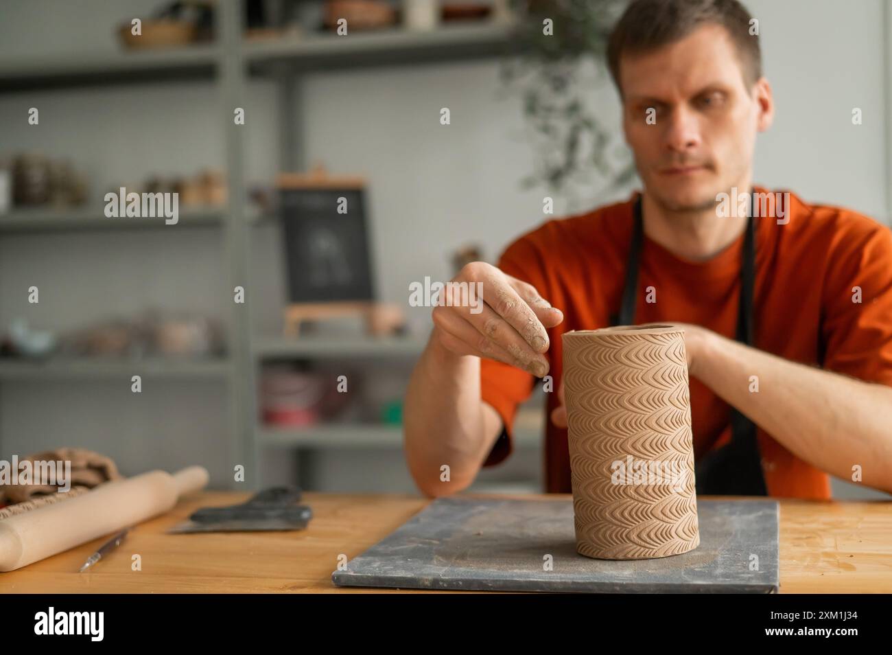 Potter sculpts a patterned cylinder from clay Stock Photo - Alamy