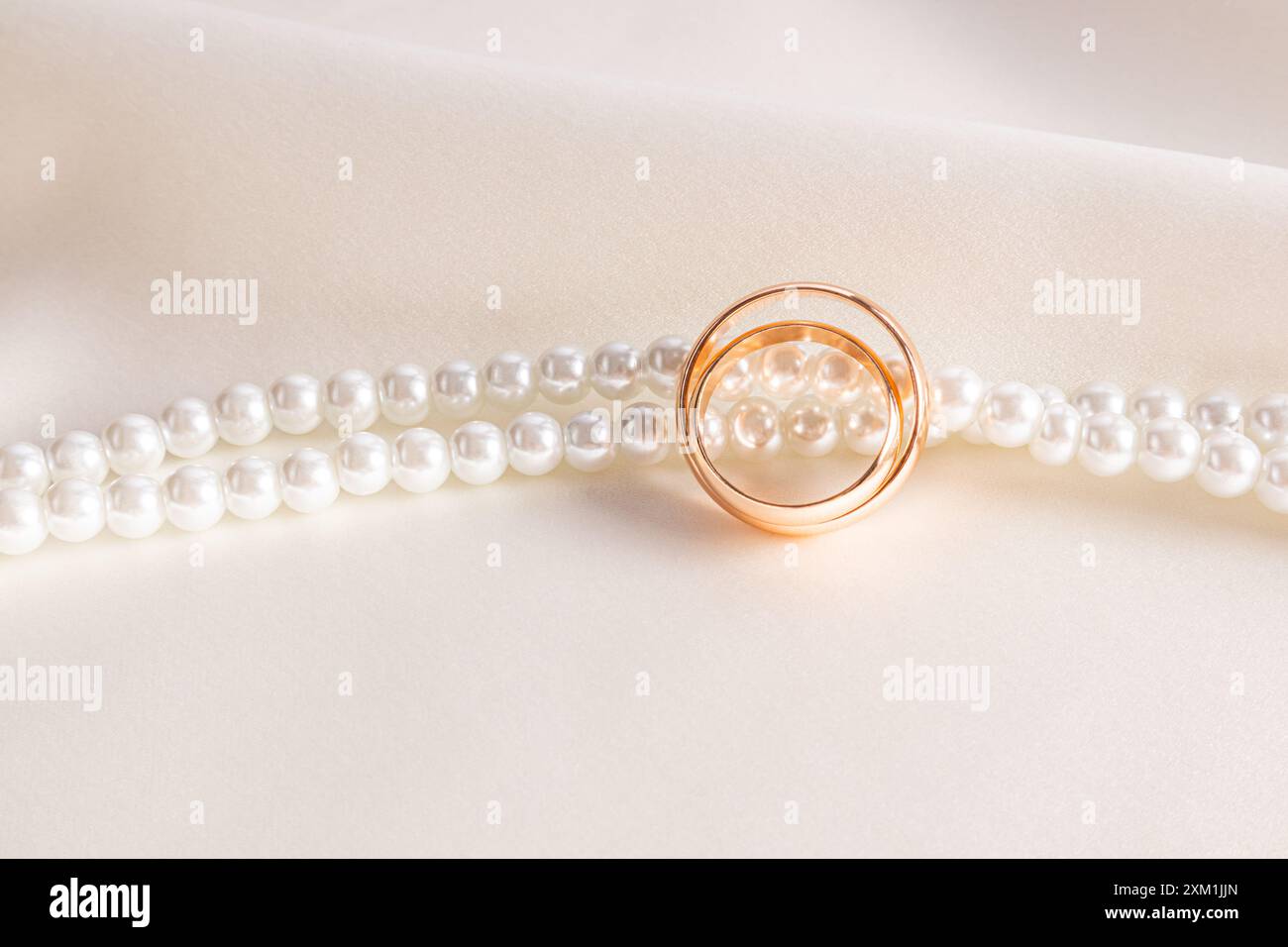 Two elegant gold wedding rings against a string of pearl beads and ...