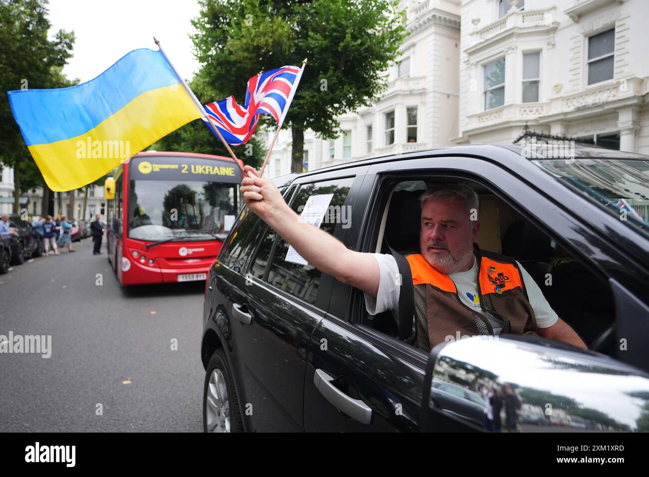 A driver waves flags as vehicles scrapped under the Ultra Low Emission ...