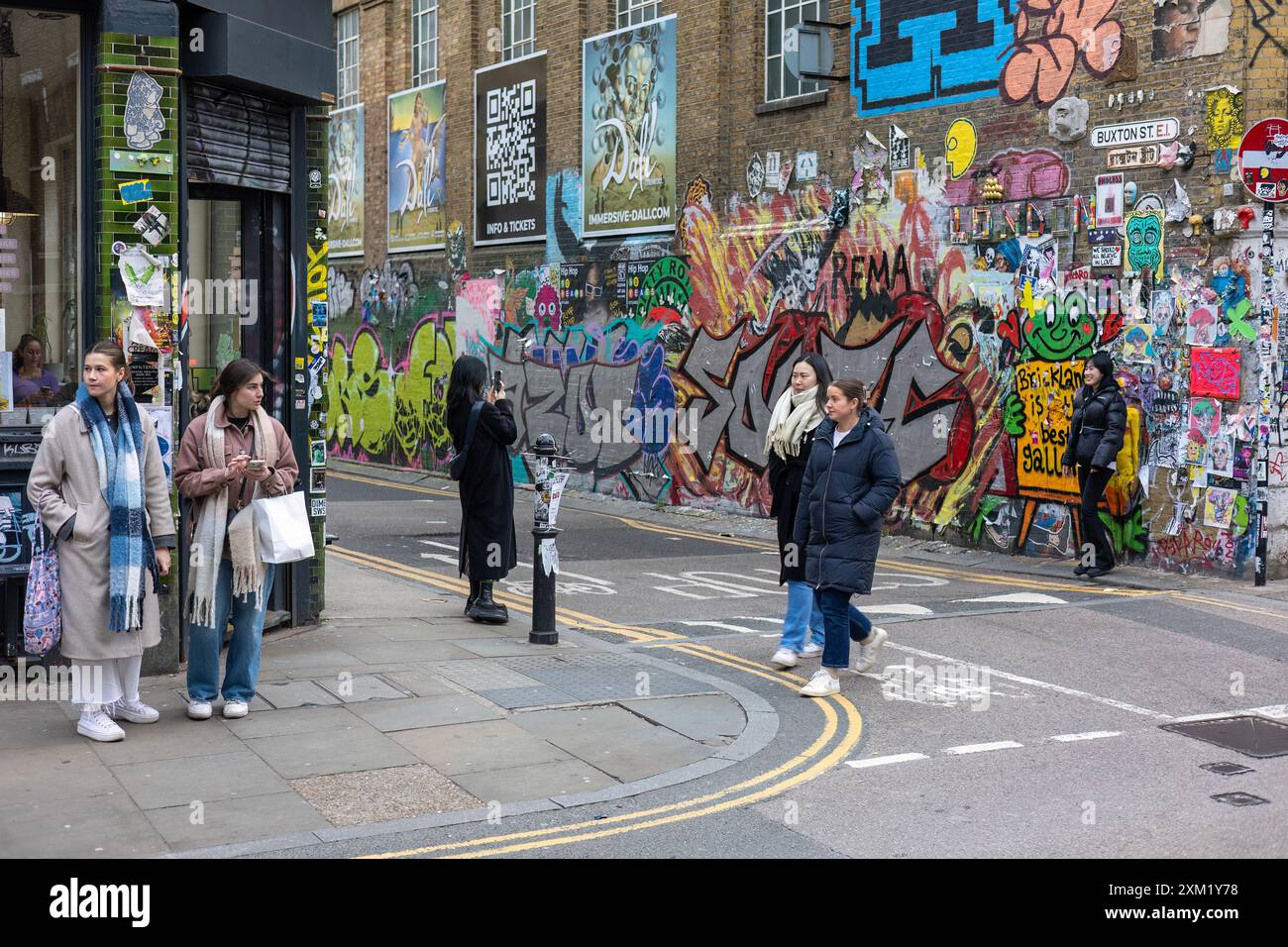 Pedestrians walk in front of walls covered in graffiti, London Stock ...