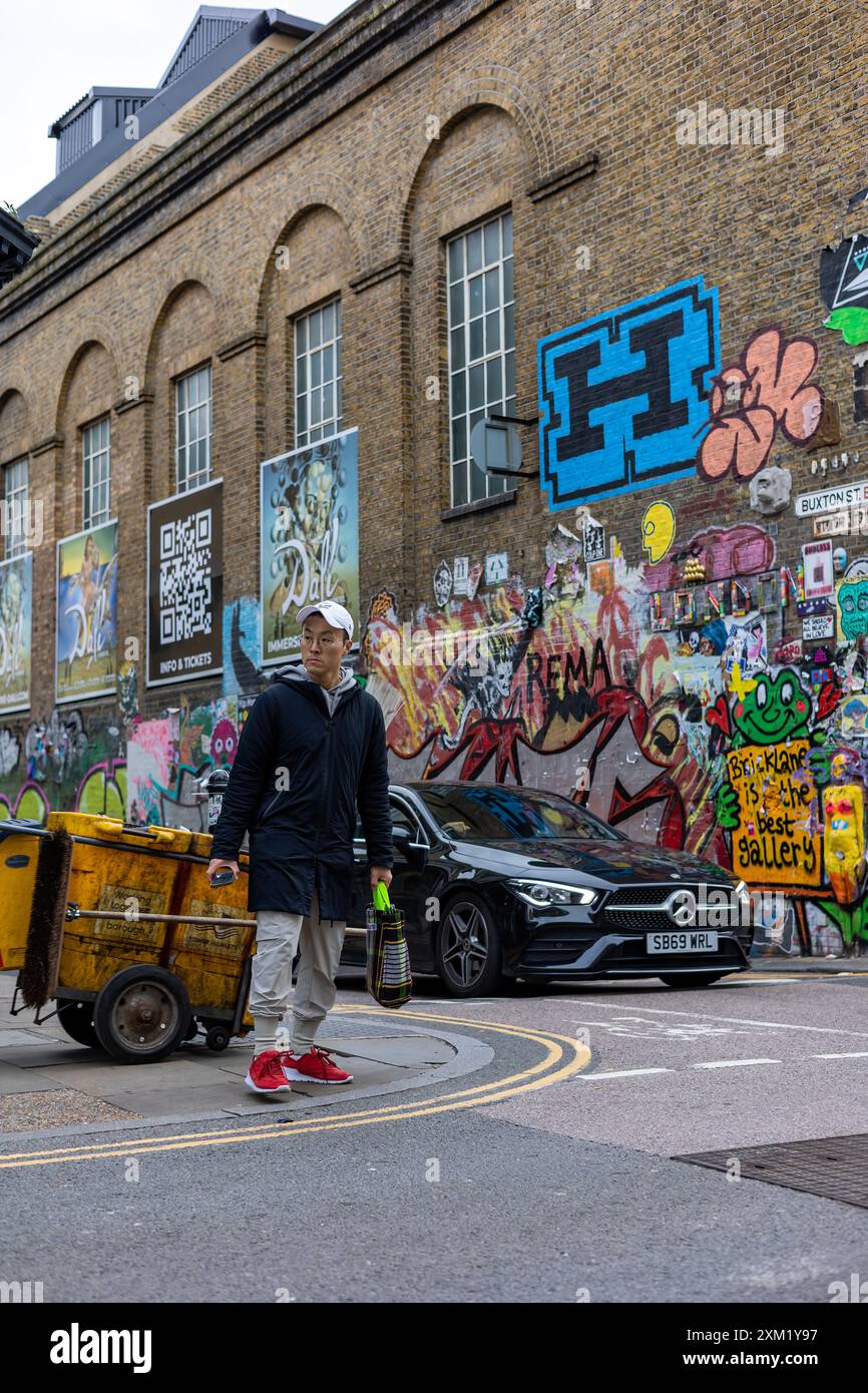 Pedestrian in red sneakers and black Mercedes by a wall covered in ...