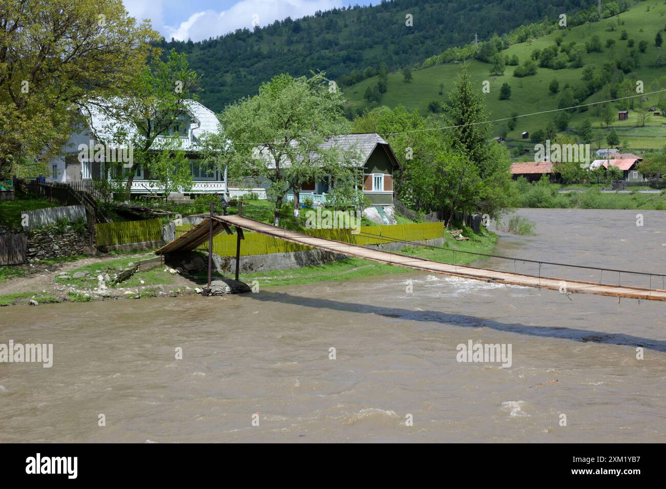 Suspension footbridge across fast-flowing river in the Carpathian ...