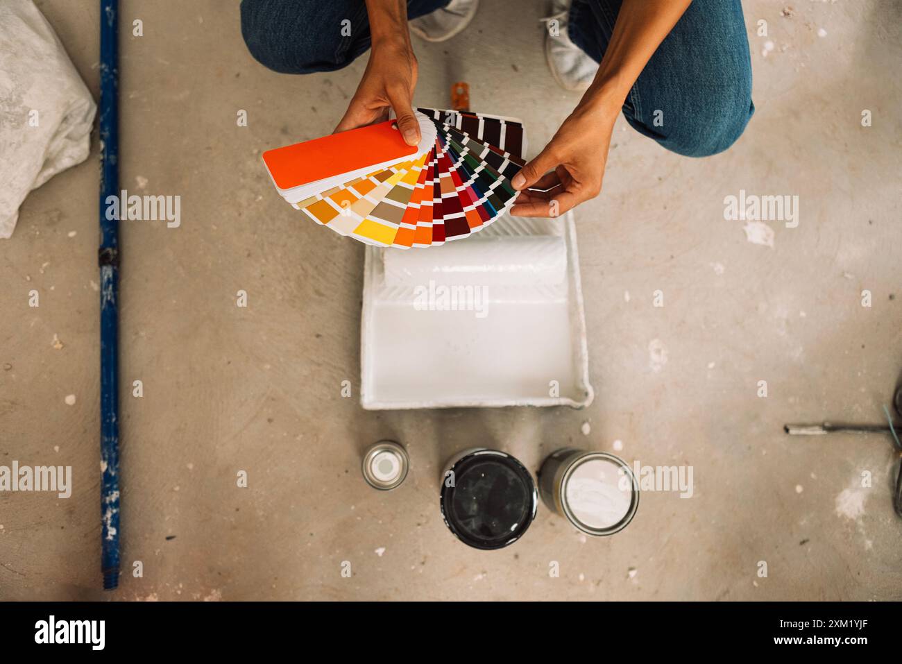 Close-up of female hands holding palette of colors, cans and paint tray ...