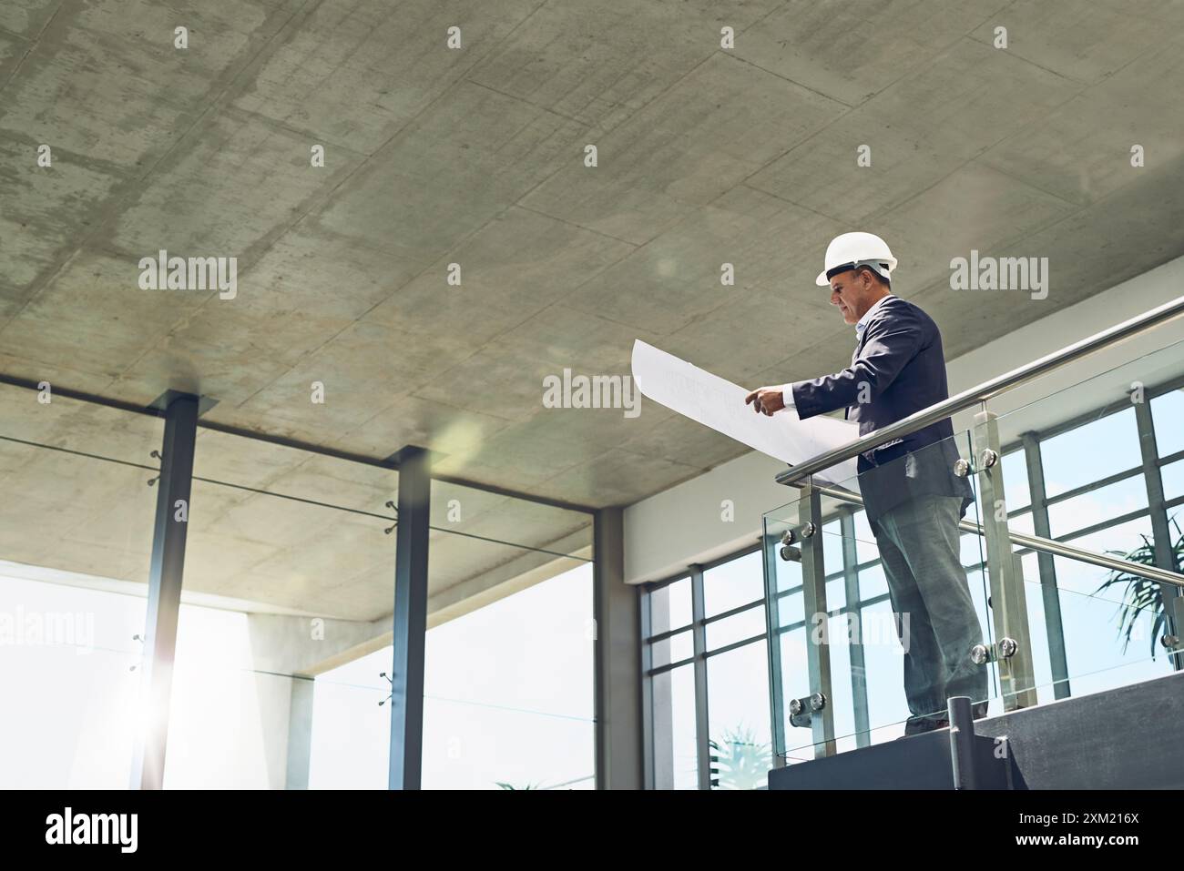 Blueprint, architect and man reading at construction site for office ...