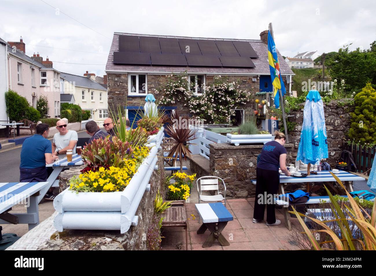 People sitting in outside pub garden at picnic tables in summer 2024 ...