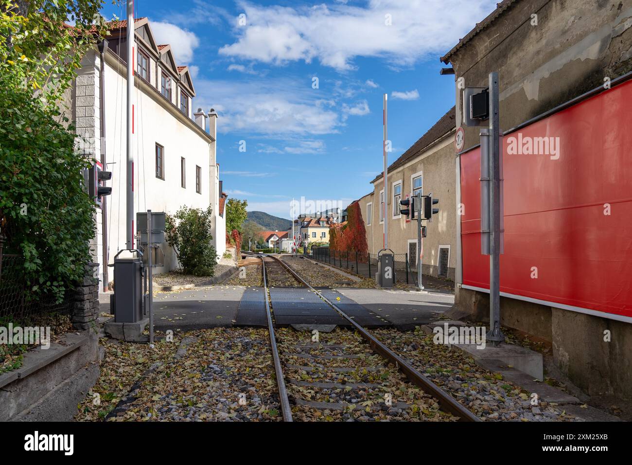 Train tracks in an Austrian town with a red wall and fall leaves Stock ...