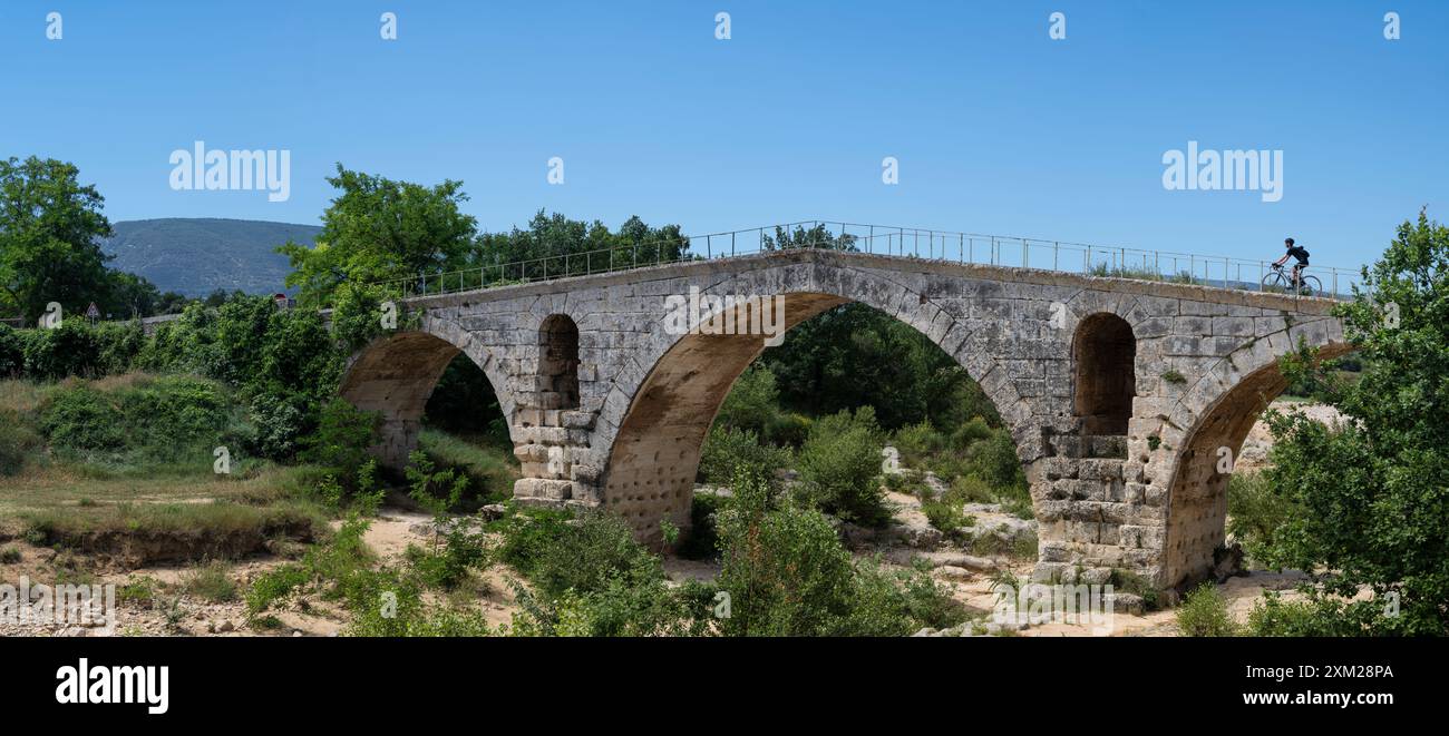 Male road cyclist riding over the 2000 year old Roman bridge, Pont ...