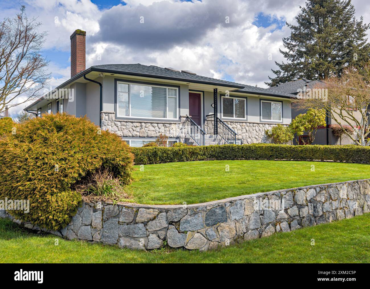 Average residential house with green lawn on land terrace in front ...