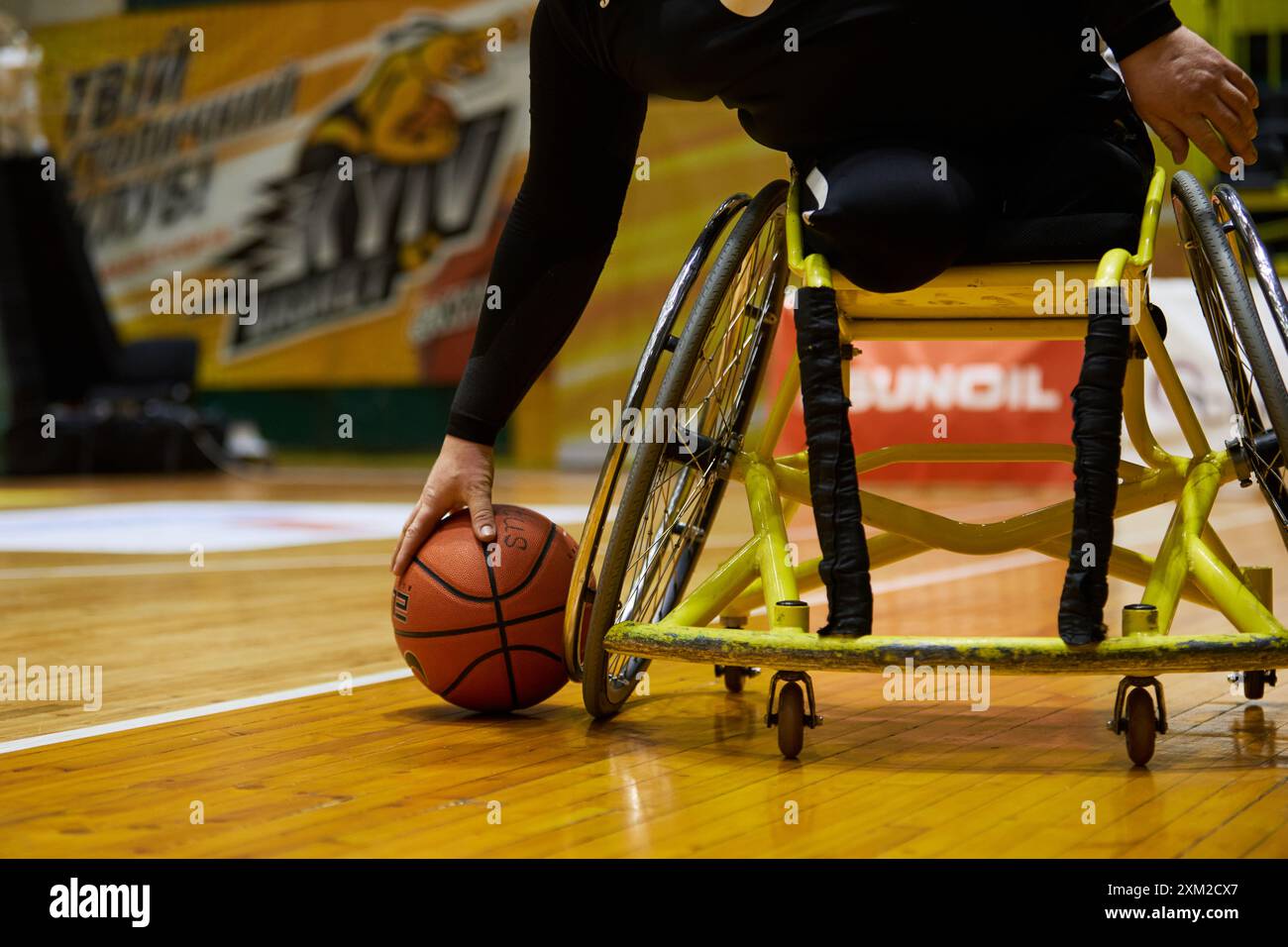 Adaptive basketball player in a wheelchair picking up the ball. Amputee ...