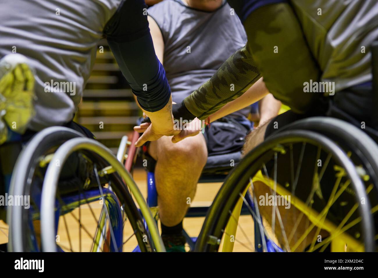 Team of adaptive basketball players in wheelchairs joining hands before ...