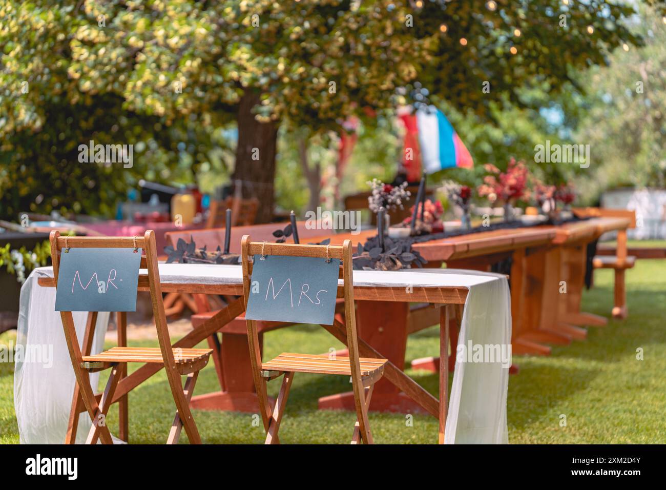 Outdoor wedding reception setup with Mr. and Mrs. signs on chairs under ...