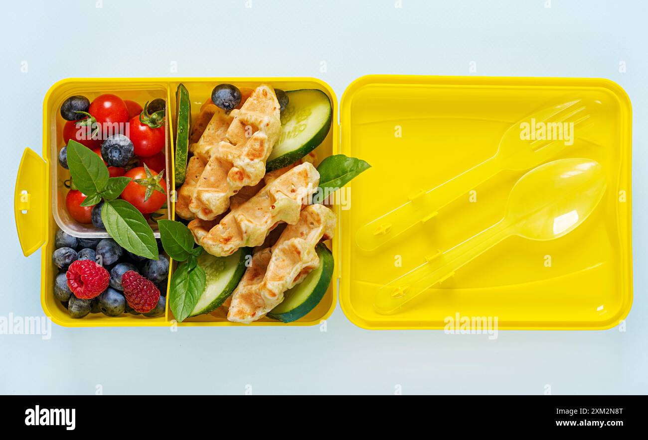 Kids lunch box with zucchini waffles, cucumber, cherry tomatoes and ...