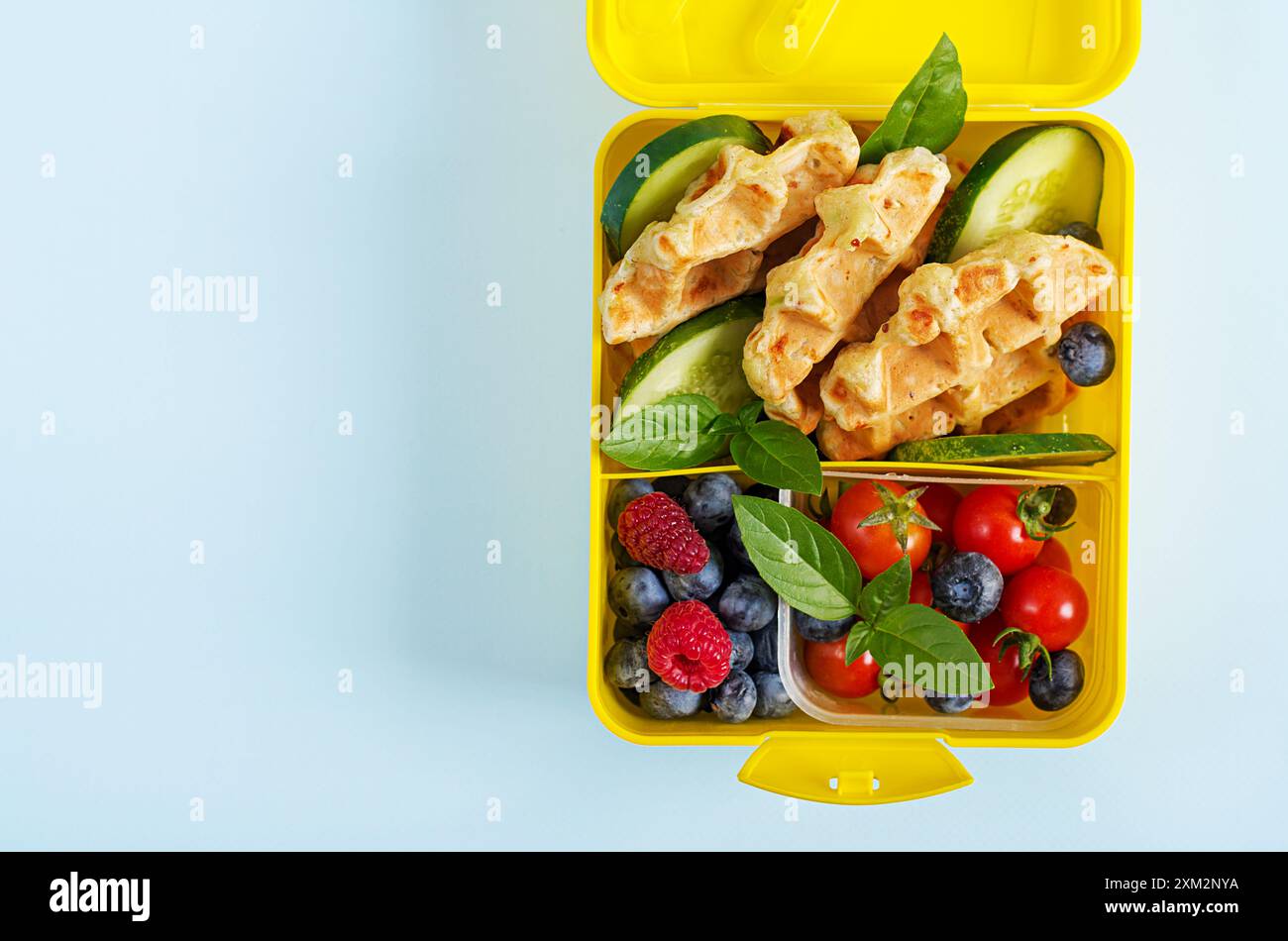 Kids lunch box with zucchini waffles, cucumber, cherry tomatoes and ...
