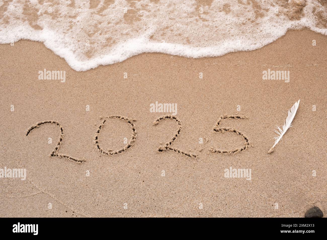 New Year 2025 written on the sand of a beach with a feather Stock Photo ...