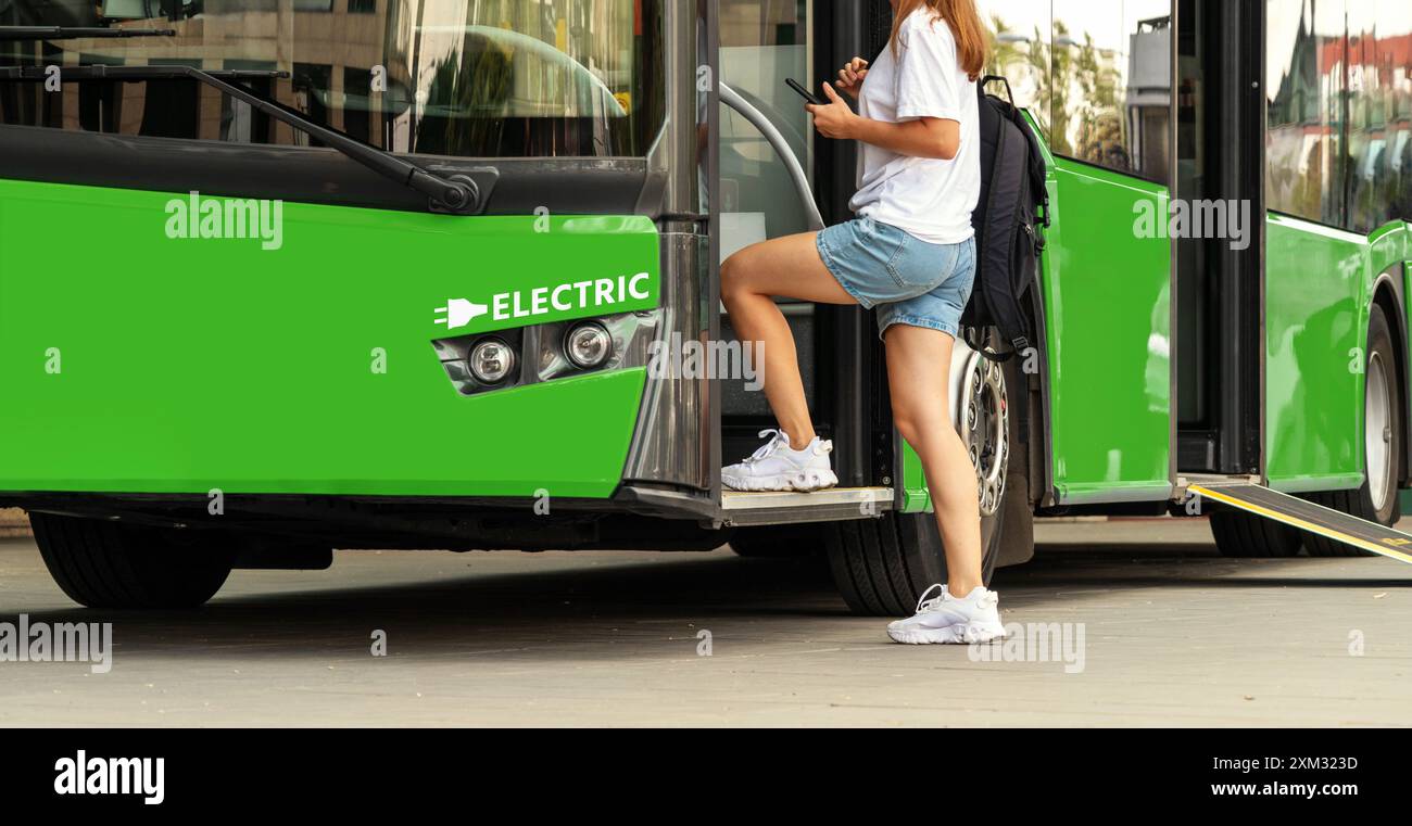 Female passenger gets on the green coloured electric bus at a bus stop ...