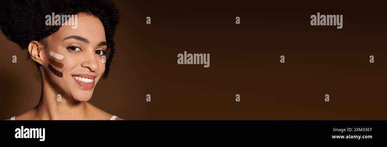 A young African American woman smiles confidently as she models makeup ...