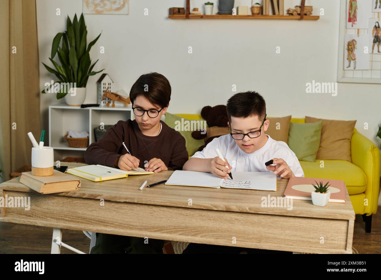 Two boys, one with Down syndrome, work on homework at a table in a home ...