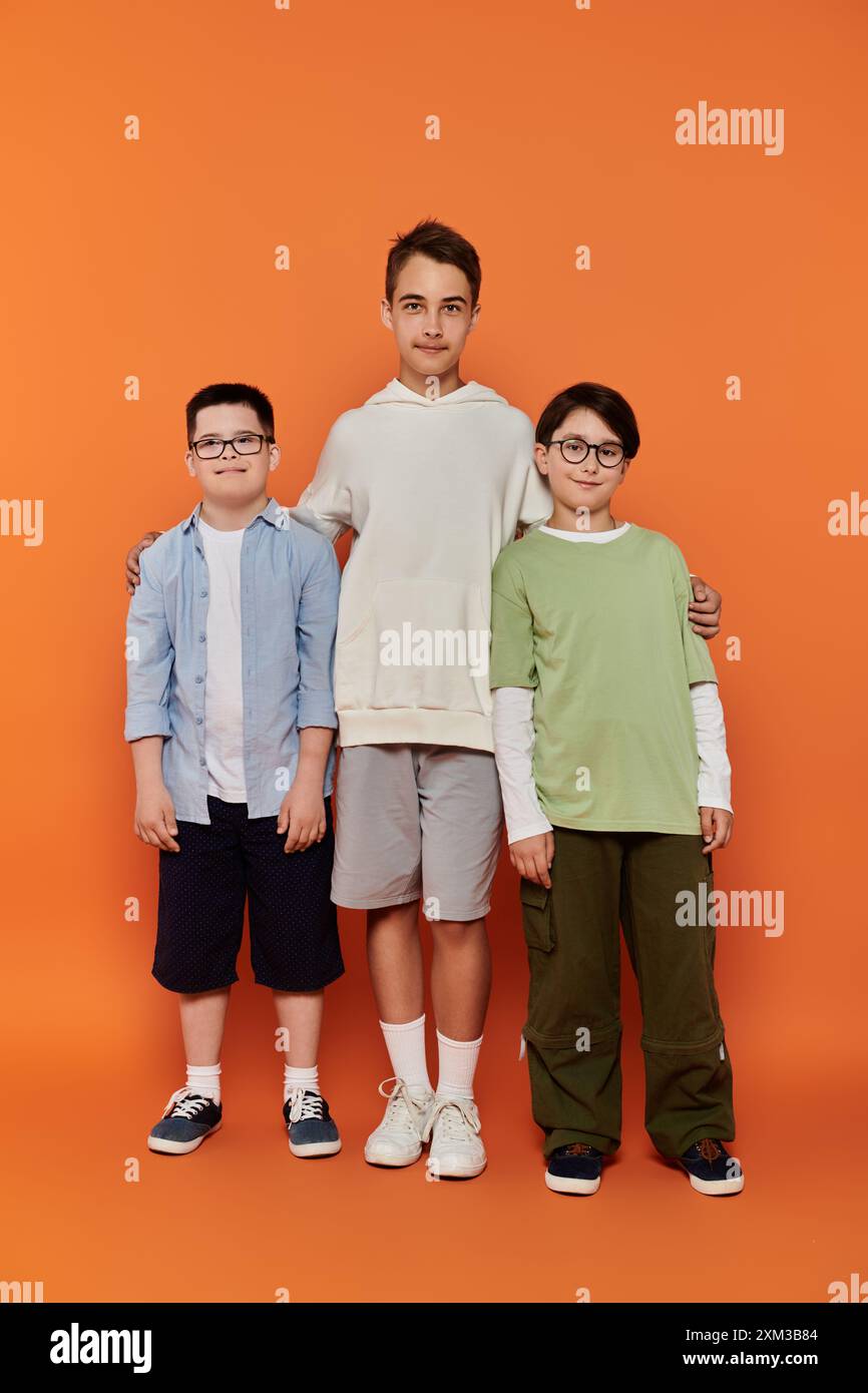 Three young boys stand together in front of an orange background Stock ...