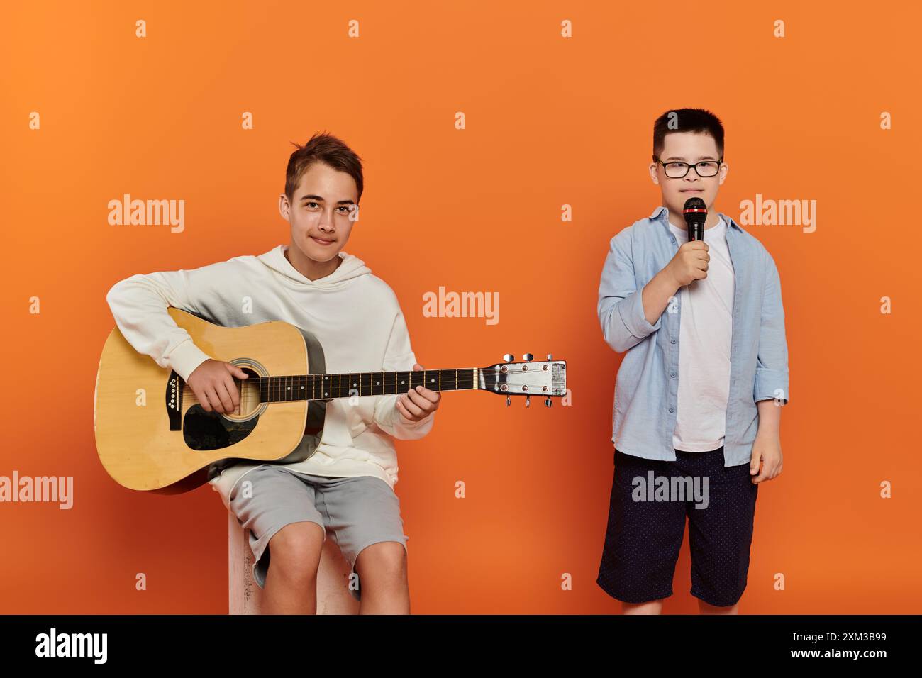 Two young boys, one playing guitar and the other singing into a ...