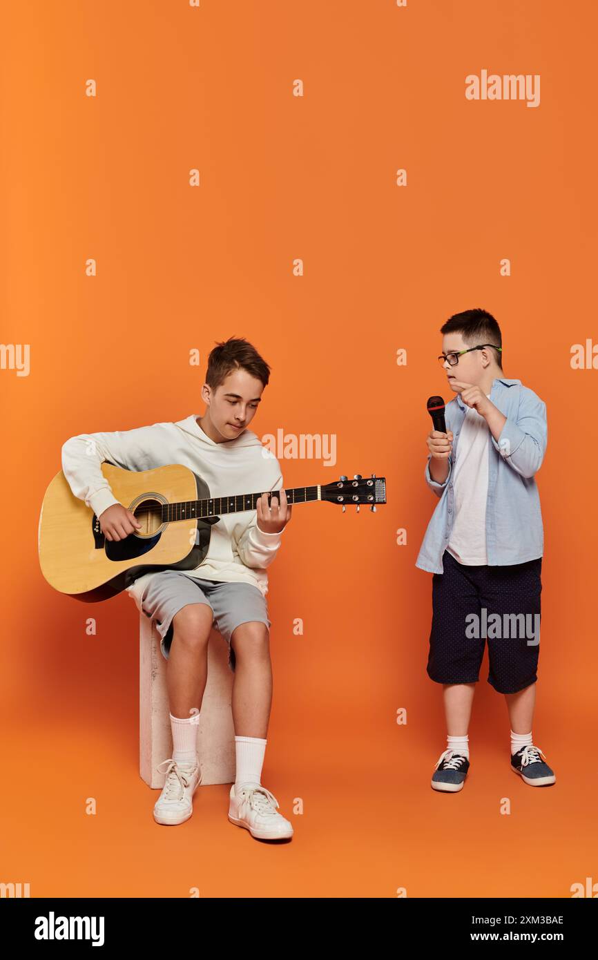 Two boys having a musical moment: one on guitar, the other singing into ...