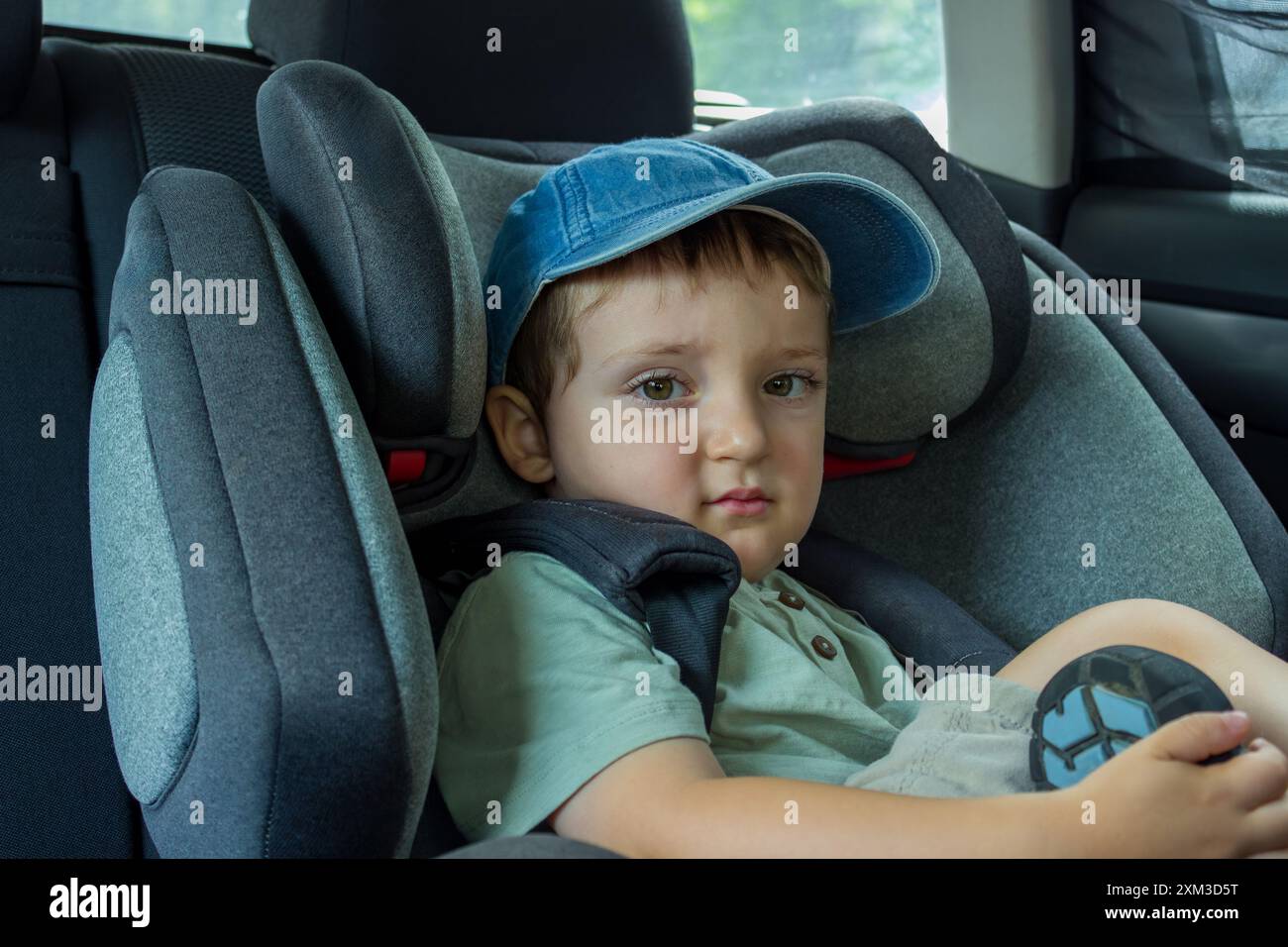 Portrait of a bored little boy sitting in a car seat. Safety of ...