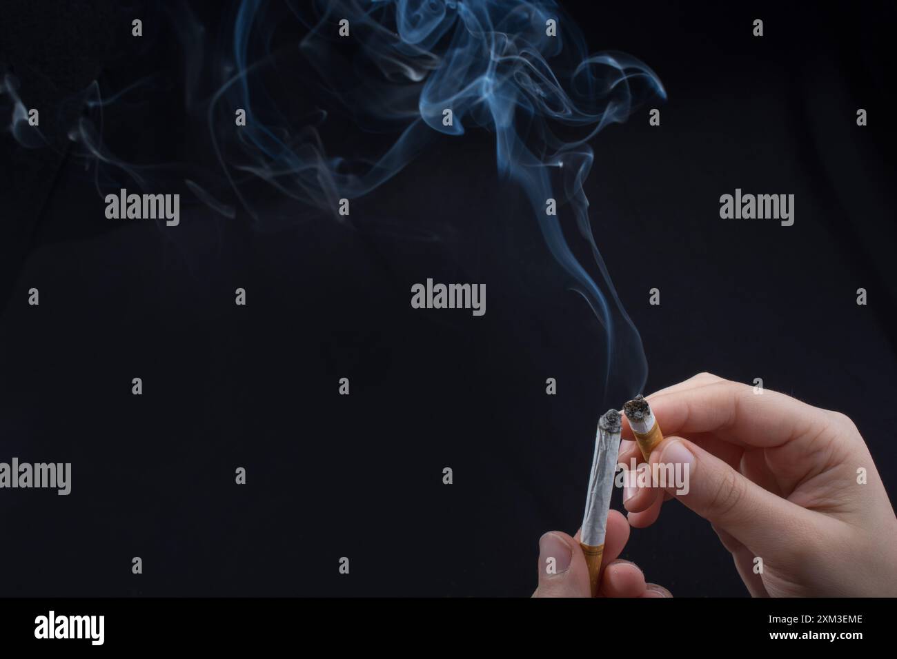 Hand is holding smoking cigarette with smoke around Stock Photo - Alamy