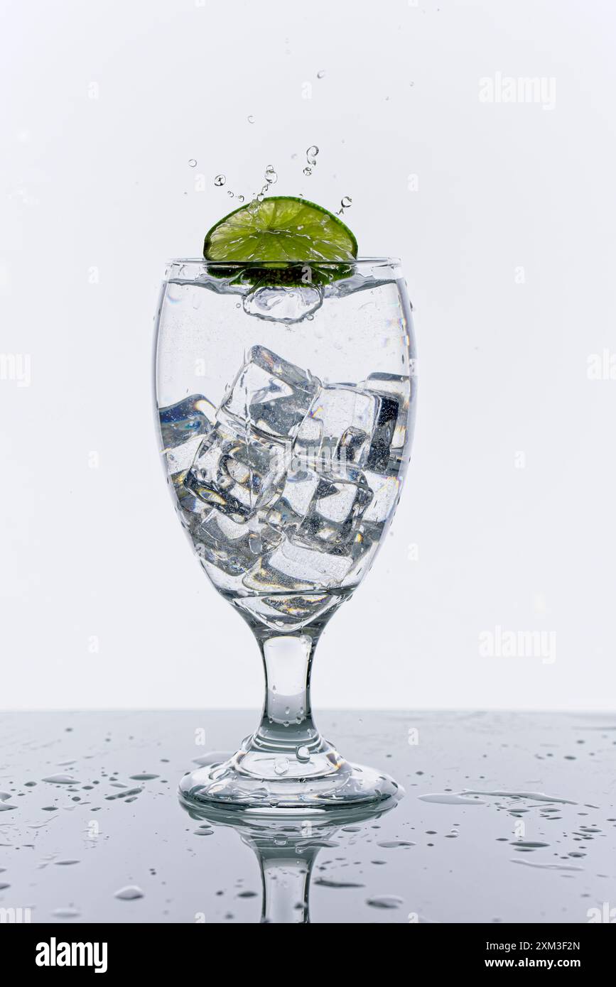A studio concept photo of dropping a slice of lime into a water glass making a splash Stock ...
